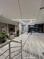 Um hall moderno com piso de mármore, área de estar e escada.