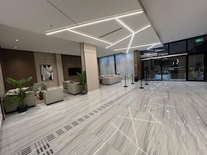 Um hall moderno com piso de mármore, área de estar e entrada de vidro.