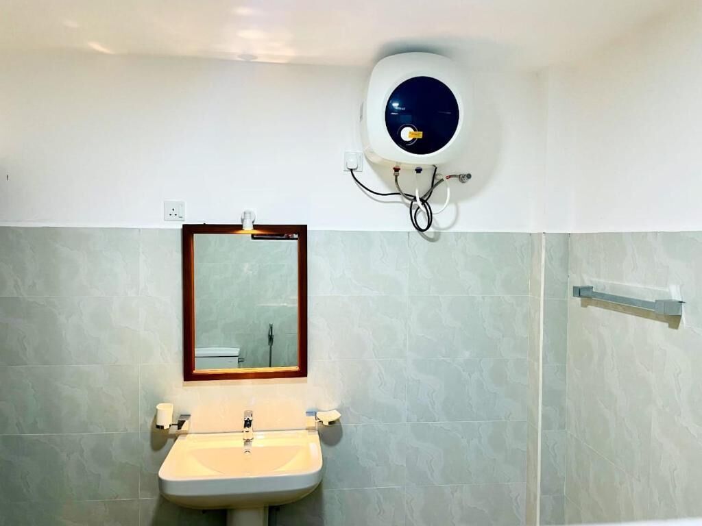 Casa de banho com lavatório, espelho e purificador de ar fixado na parede.
