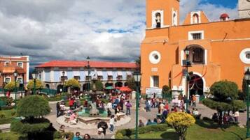 Uma praça pública com uma fonte central, rodeada por edifícios com estilos arquitetônicos diferentes.