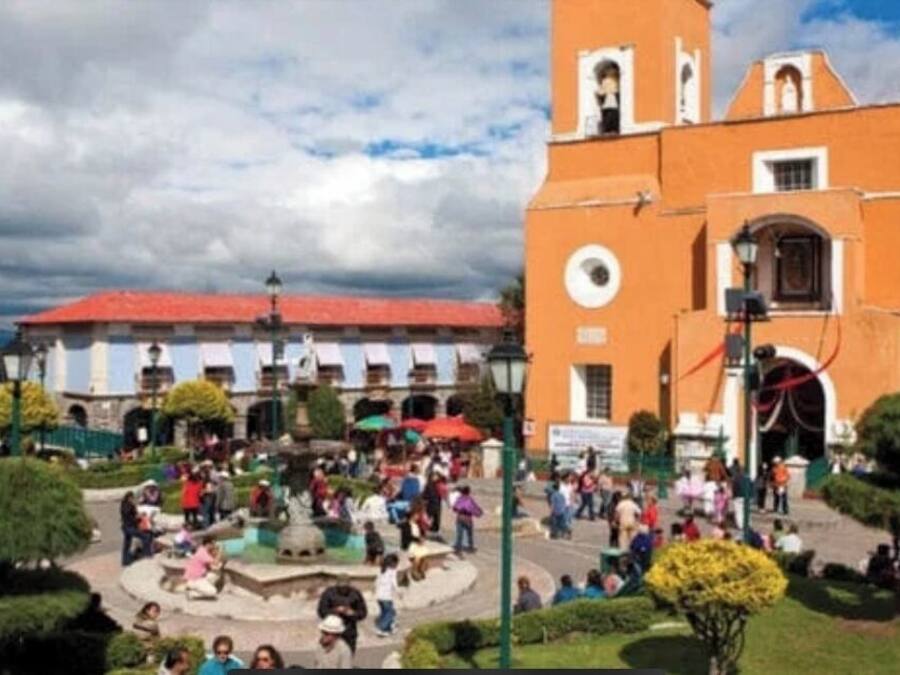 Uma praça pública com uma fonte central, rodeada por edifícios com estilos arquitetônicos diferentes.