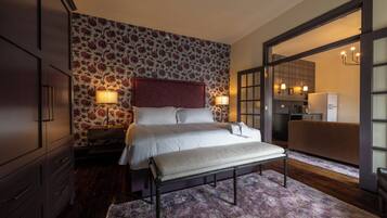 Quarto com uma cama grande, um banco, uma cômoda e uma mesa de cabeceira.
