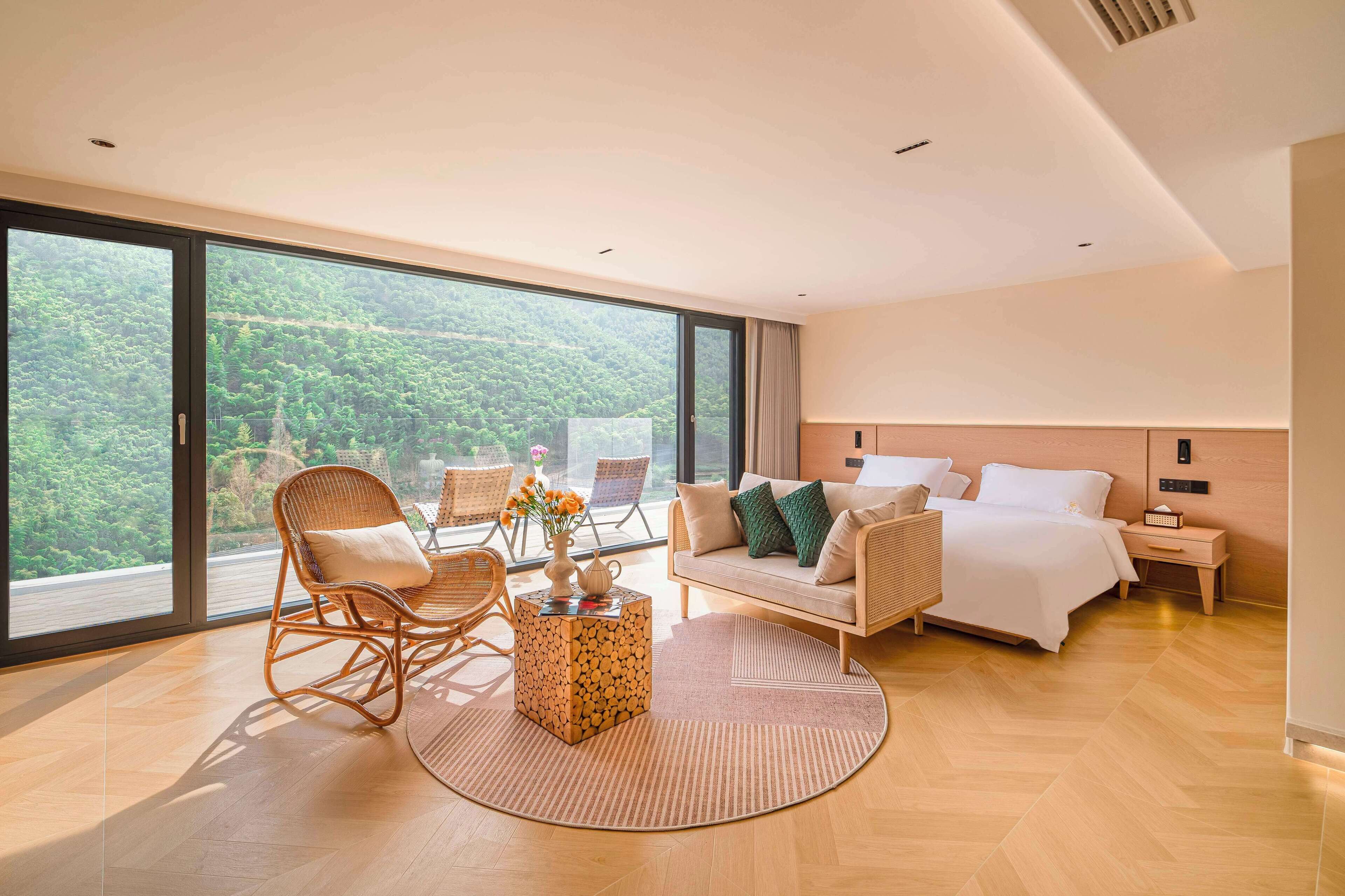 Quarto de hotel moderno com uma varanda grande, uma cama, um sofá e uma área de jantar.