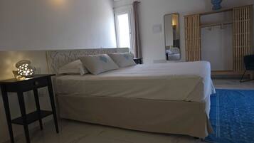 Quarto de hotel com cama, mesa de cabeceira, luminária, ar condicionado e um tapete azul.