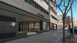 Um edifício moderno com uma vitrine identificada como 'FLIPCO RETRO' e uma árvore em primeiro plano.