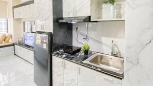 Cozinha moderna com bancadas de mármore, pia de aço inoxidável e coifa preta.