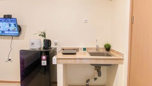 Uma cozinha compacta com pia embutida, micro-ondas e um pequeno balcão.