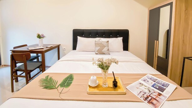 Quarto bem arrumado com cama, mesa de cabeceira, cadeira e escrivaninha.