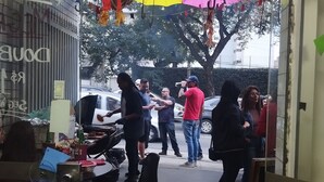 Um carrinho de comida de rua com uma churrasqueira, uma cadeira e uma mesa com diversos produtos.