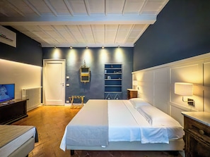 Um quarto moderno com uma cama grande, uma televisão, um radiador e uma estante.