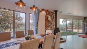 Uma sala de jantar moderna com mesa de madeira, cadeiras bege e luminárias pendentes.
