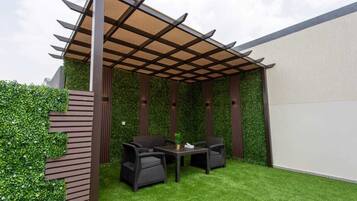 Área de pátio com pérgola, parede verde e mobiliário de exterior.