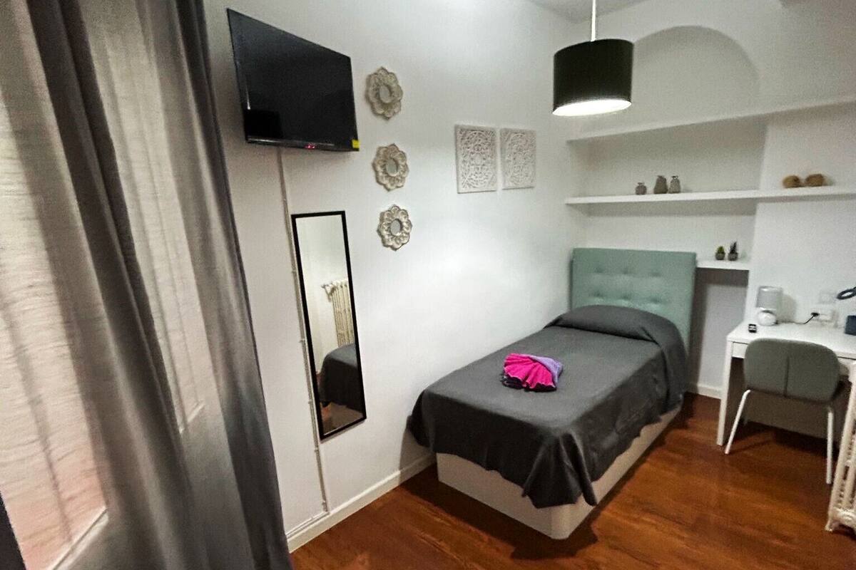 Quarto moderno com cama, escrivaninha e televisão.