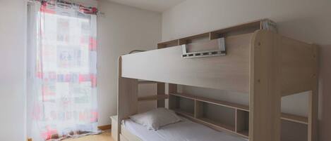 Quarto com beliche, janela, cortina e luminária suspensa.