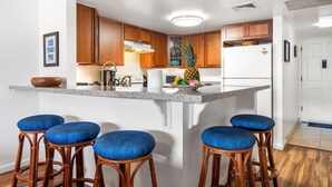 Uma cozinha com armários de madeira, uma geladeira branca e uma ilha central com banquetas.