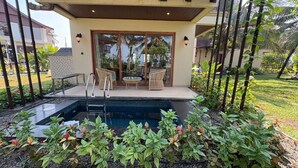 Uma área de piscina com estrutura de vidro, mobiliário ao ar livre e vegetação ao redor.