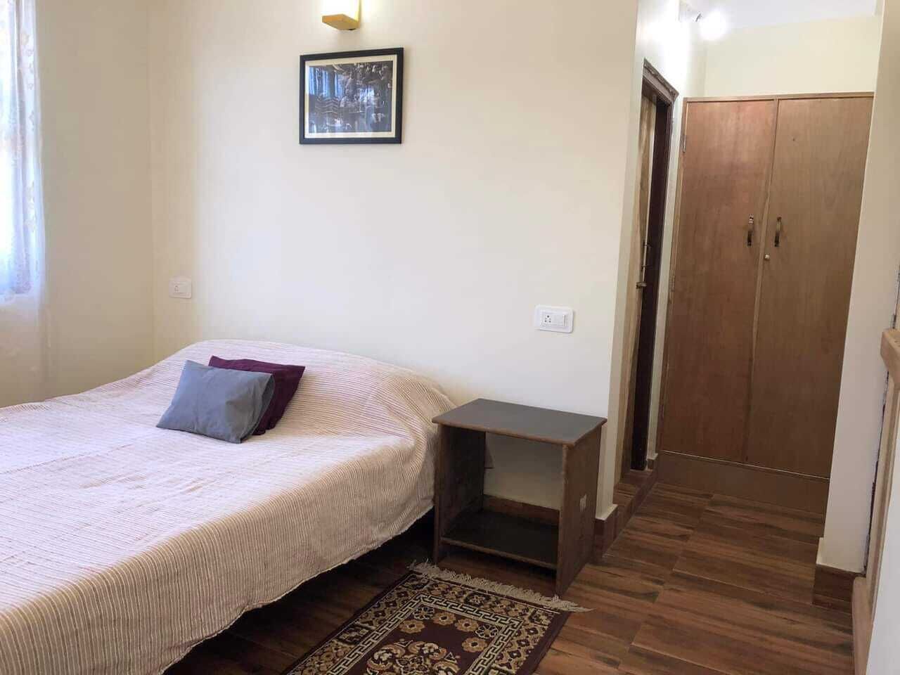 Quarto com cama, mesa de cabeceira, guarda-roupa e tapete.