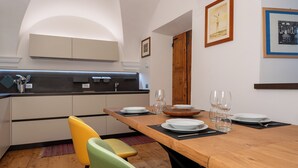 Cozinha moderna com mesa de jantar de madeira para quatro pessoas, uma cadeira amarela e verde, e uma porta de madeira.