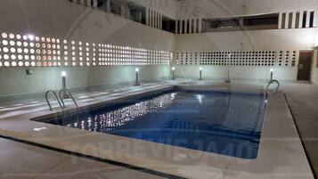 Piscina interior com piso ladrilhado e água com tonalidade azul.