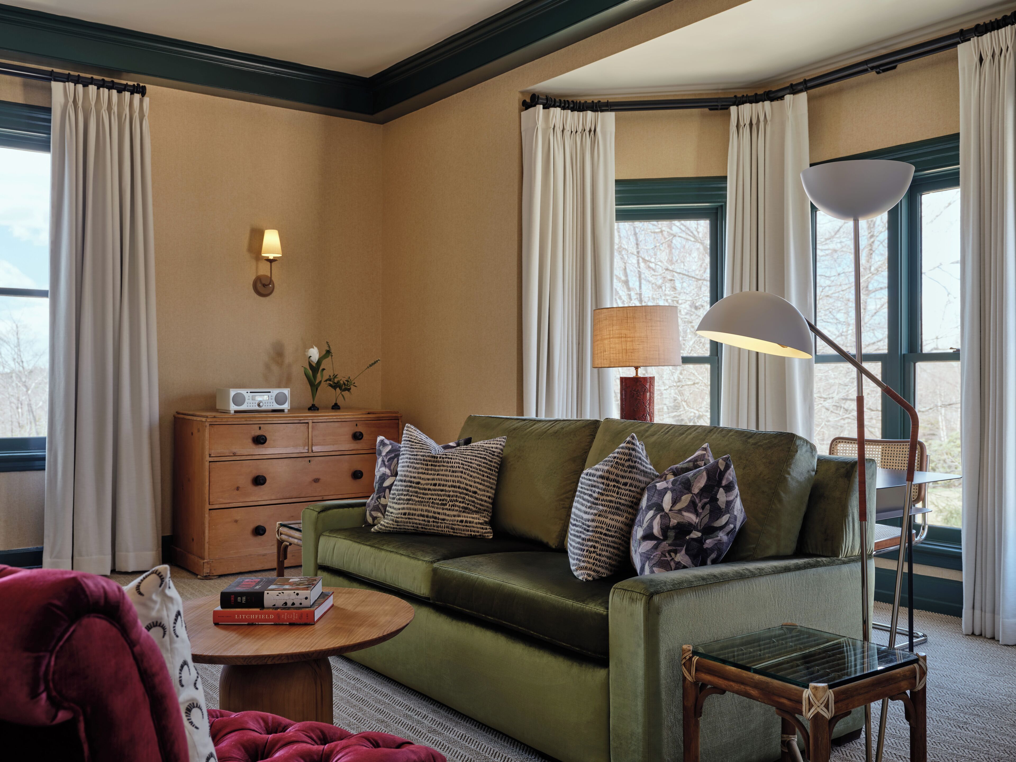 Um quarto aconchegante com um sofá verde, cômoda de madeira e uma mesa de vidro.