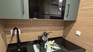 Uma cozinha compacta com micro-ondas integrado, pia e máquina de café no balcão.