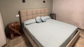 Quarto com cama, mesa de cabeceira e luminária na parede.