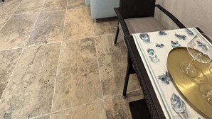 Uma sala de estar com sofá, televisão, mesa de jantar com um jogo americano decorativo e tapete estampado.