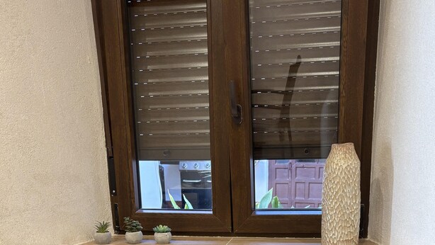 Lareira com frente de vidro, manto de madeira e um vaso sobre o manto.