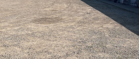 Um estacionamento de cascalho com uma fileira de cabines no estilo motel, um SUV estacionado e um trailer de barco.