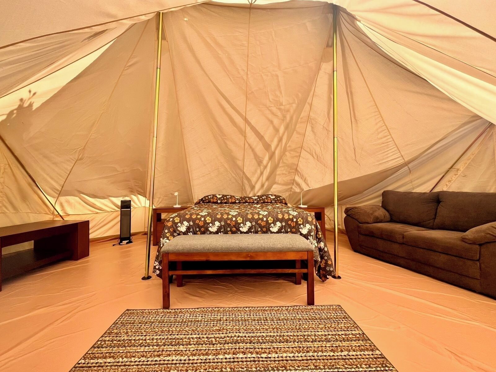 Uma tenda com uma cama, um sofá e uma pequena mesa.