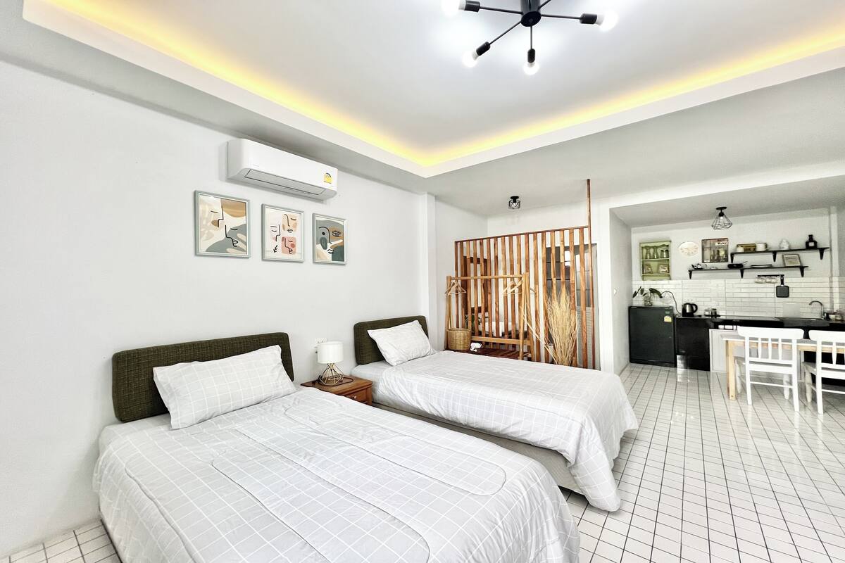 Quarto de hotel moderno com duas camas, uma kitchenette e um espaço para refeições.