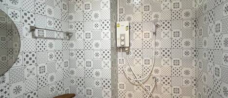 Casa de banho com azulejos estampados, sanita, lavatório e chuveiro.