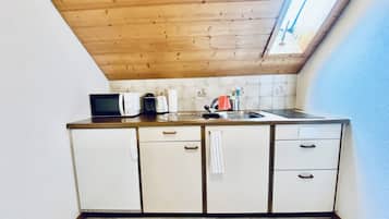 Uma cozinha compacta com teto de madeira, janela e painel de azulejos.
