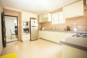 Cozinha moderna com armários brancos, eletrodomésticos de aço inoxidável e bancada de granito.