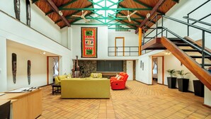 Uma sala de estar ampla com teto alto, escada e um sofá grande.