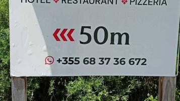 Placa de Dragobia, um hotel, restaurante e pizzaria, a 50 metros, com número de contato.