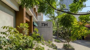 Um edifício com uma placa indicando 'nh GUADALAJARA STUDIOS' e uma escadaria rodeada de vegetação.