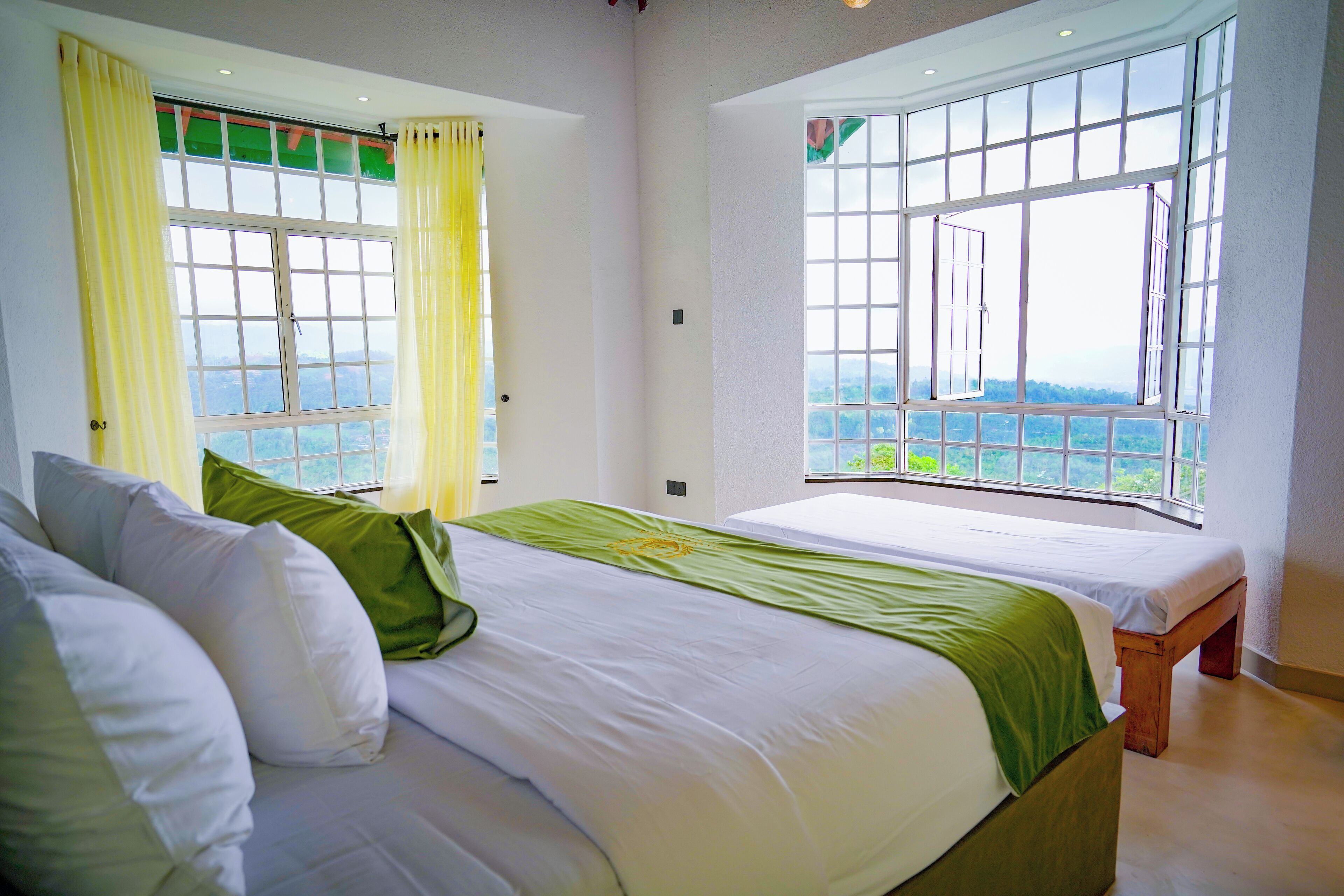 Quarto com uma cama grande, duas janelas e vista para o exterior.