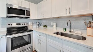 Uma cozinha moderna com armários brancos, eletrodomésticos de aço inoxidável e bancada de granito.