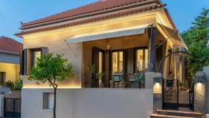 Uma casa moderna com varanda, uma pequena árvore e uma escadaria que leva à entrada.
