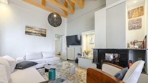 Uma sala de estar moderna com sofá branco, mesa de centro e lareira.