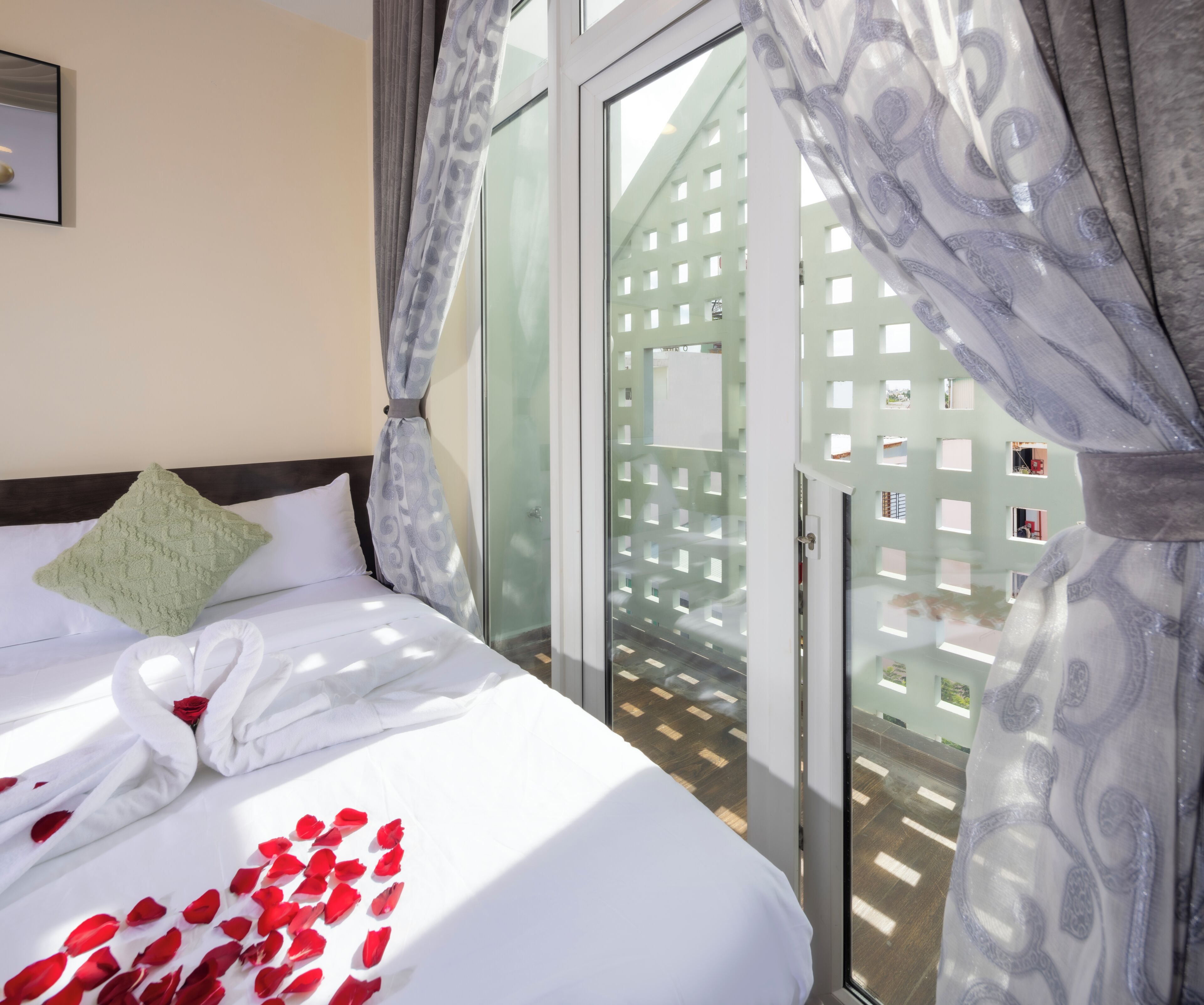 Quarto de hotel com cama, porta de vidro para uma varanda e vista de um edifício.