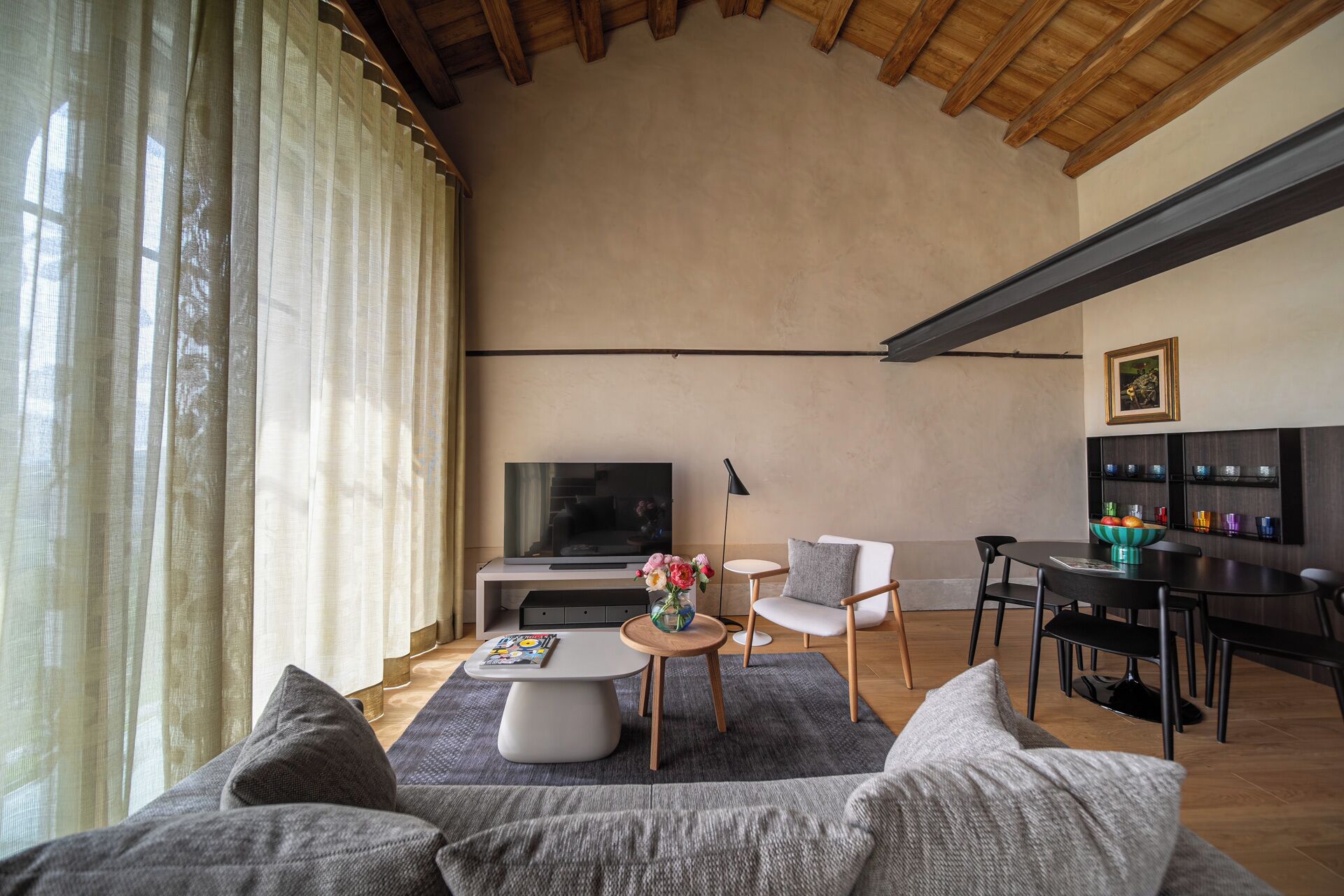Uma sala de estar moderna com sofá, mesa de centro, TV e área de jantar com cadeiras e mesa.