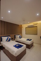Quarto de hotel com duas camas, um ventilador de teto, um ar condicionado e uma janela com persiana.