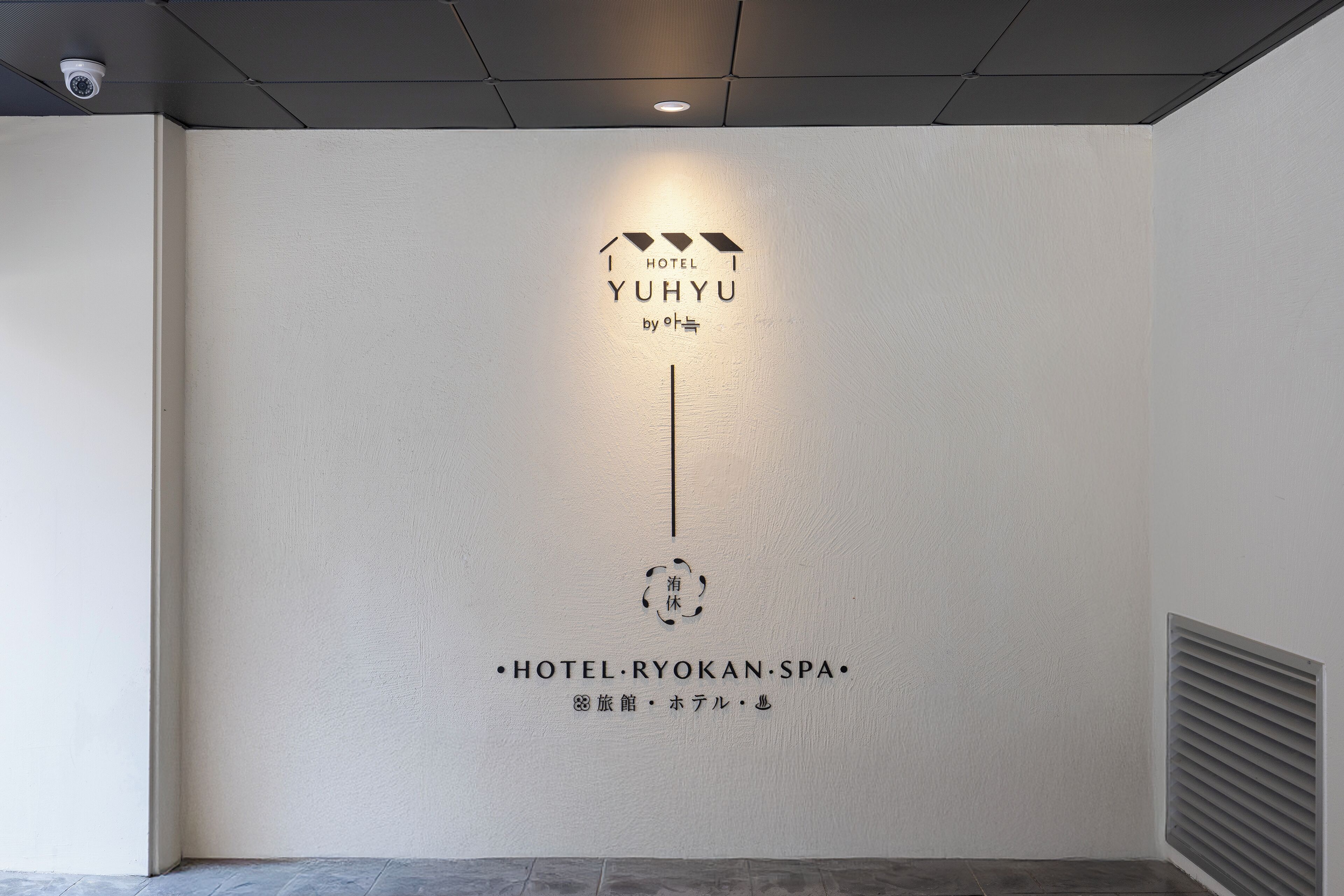Paredes com placas indicando 'HOTEL YUHYU by Okul' e 'HOTEL RYOKAN SPA', com design minimalista.