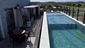 Uma piscina no terraço com vista ampla da paisagem ao redor, área de estar coberta e design arquitetônico moderno.