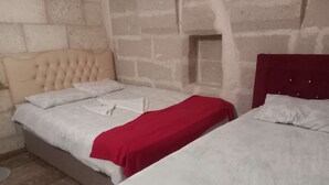 Quarto com duas camas, uma com manta vermelha e outra com manta branca.