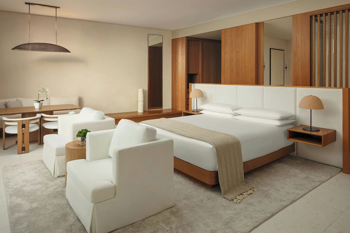 Quarto moderno com cama grande, mesas de cabeceira, escrivaninha e uma cadeira.