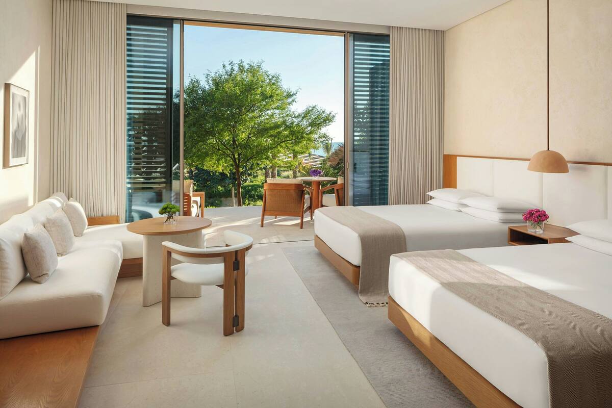 Quarto de hotel com uma janela grande, um sofá, uma cama, uma mesa pequena e uma cadeira.