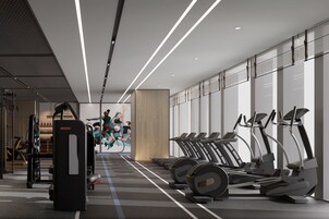 Academia moderna com esteiras, máquinas de musculação e um mural de atletas.